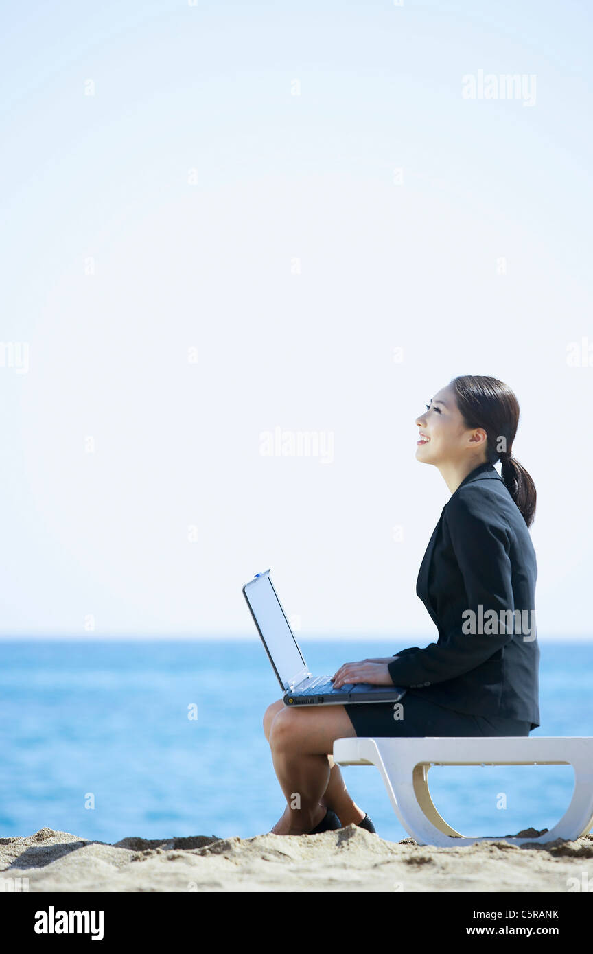A woman working on a notebook computer sitting on a chair Stock Photo ...