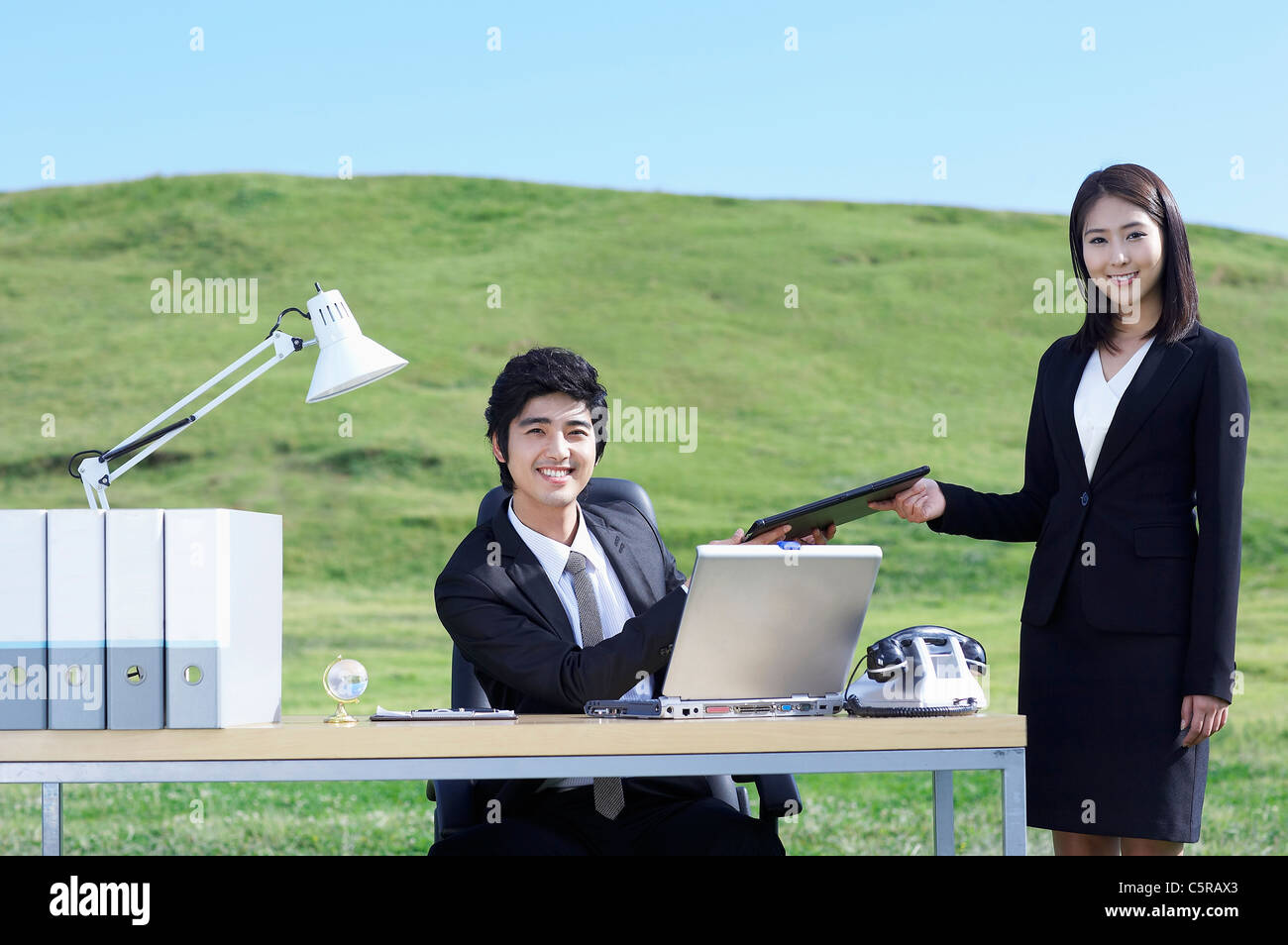 A woman giving a file to a man Stock Photo - Alamy