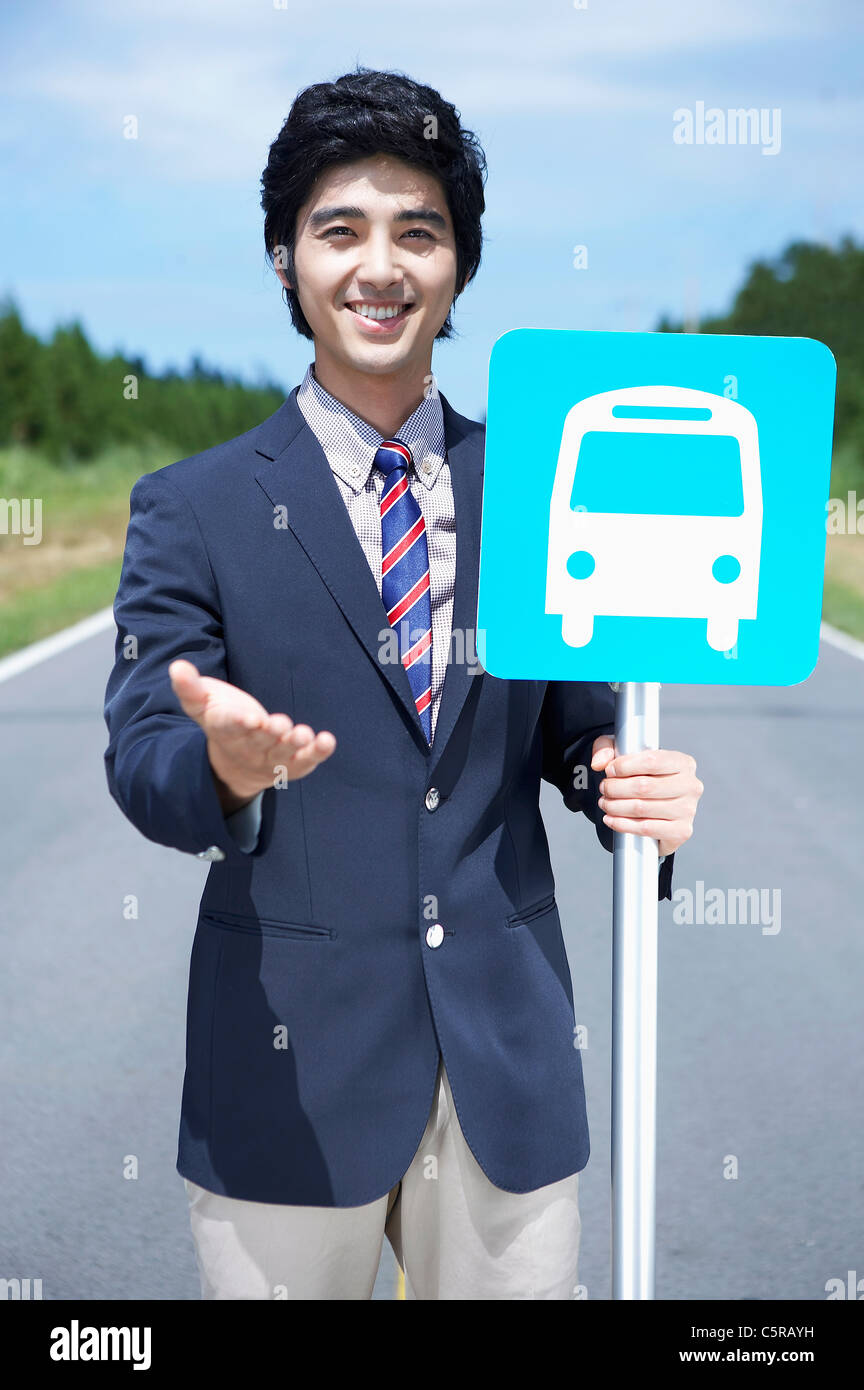A man holding a bus station sign smiling Stock Photo - Alamy