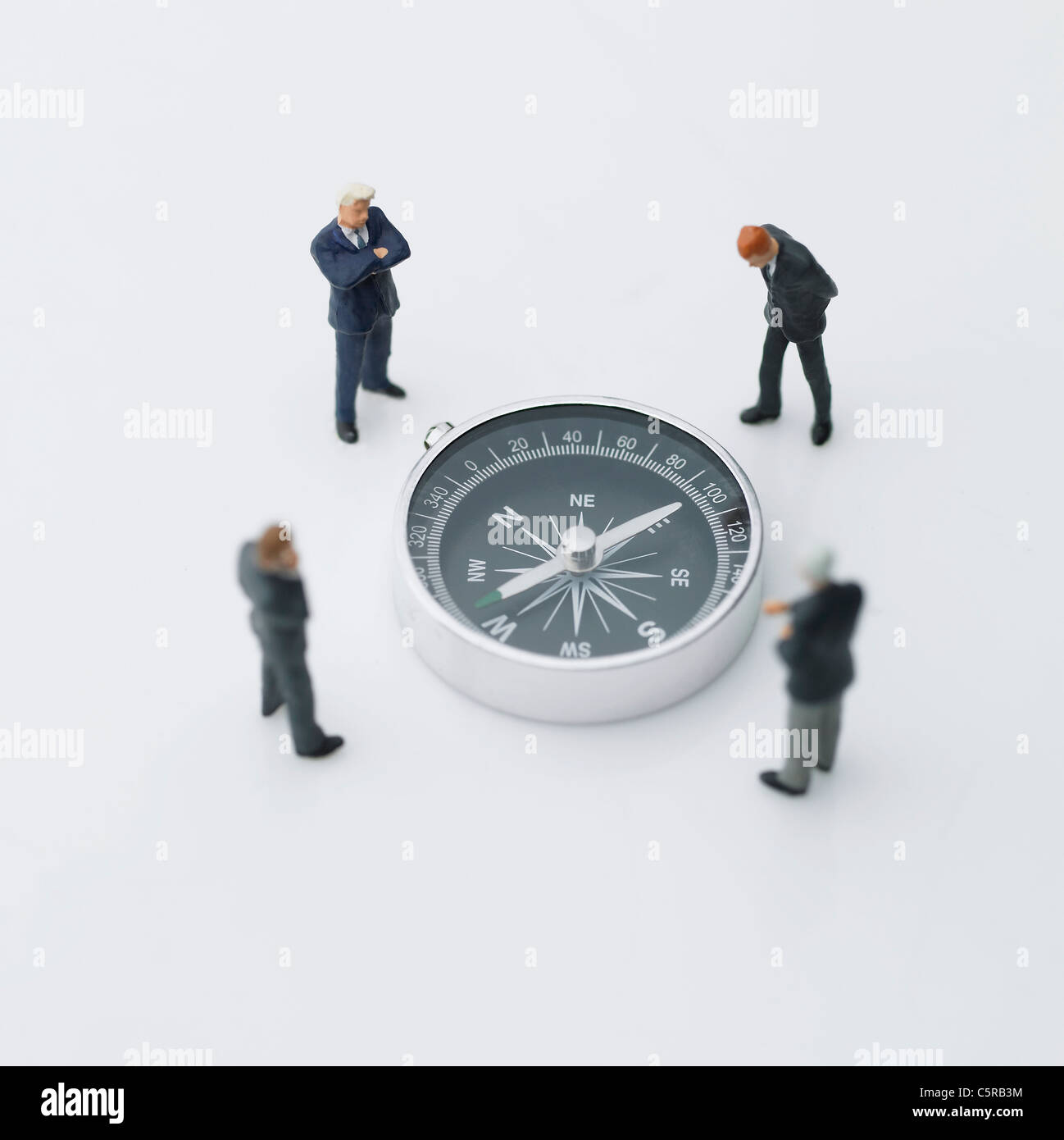 Four figurines around a compass Stock Photo - Alamy