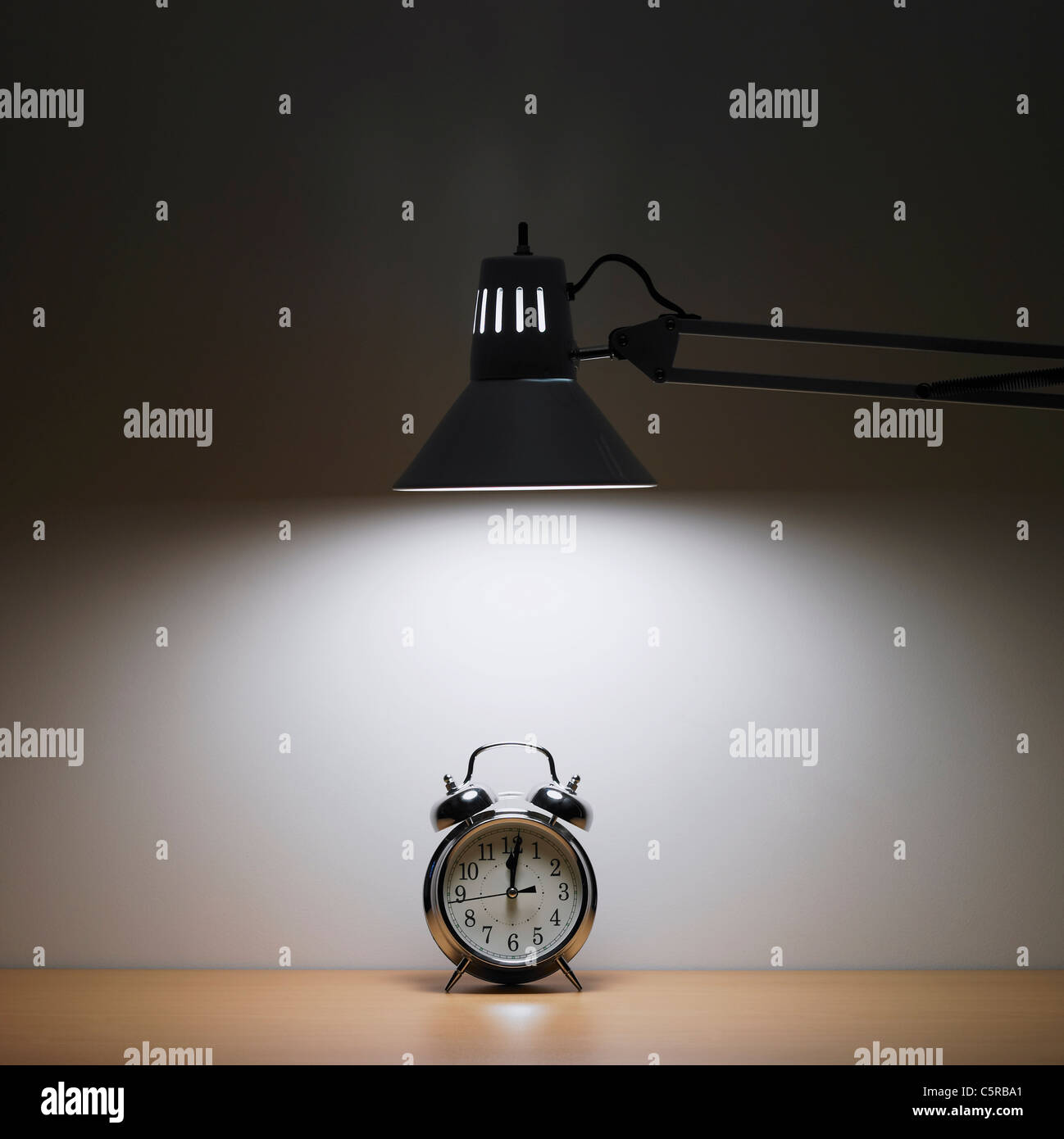 An alarm clock below a lamp Stock Photo - Alamy