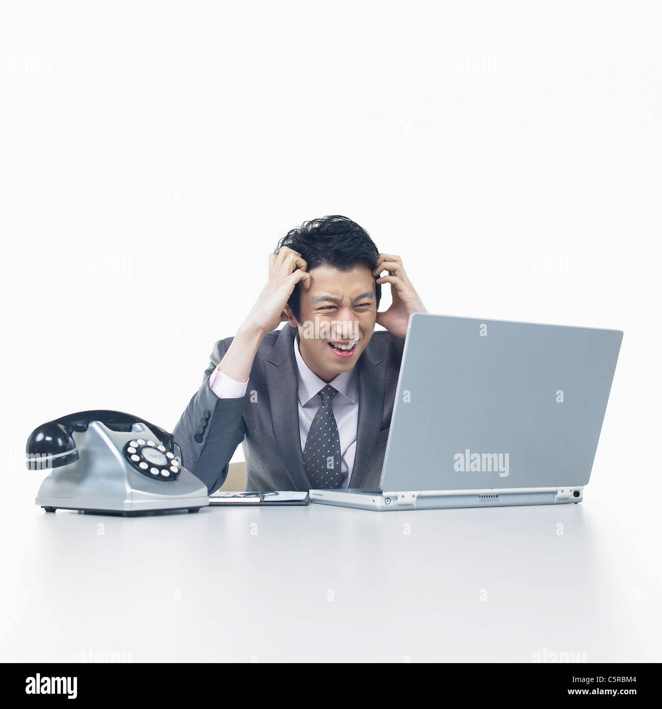 A man frowning his face looking at his laptop computer Stock Photo - Alamy