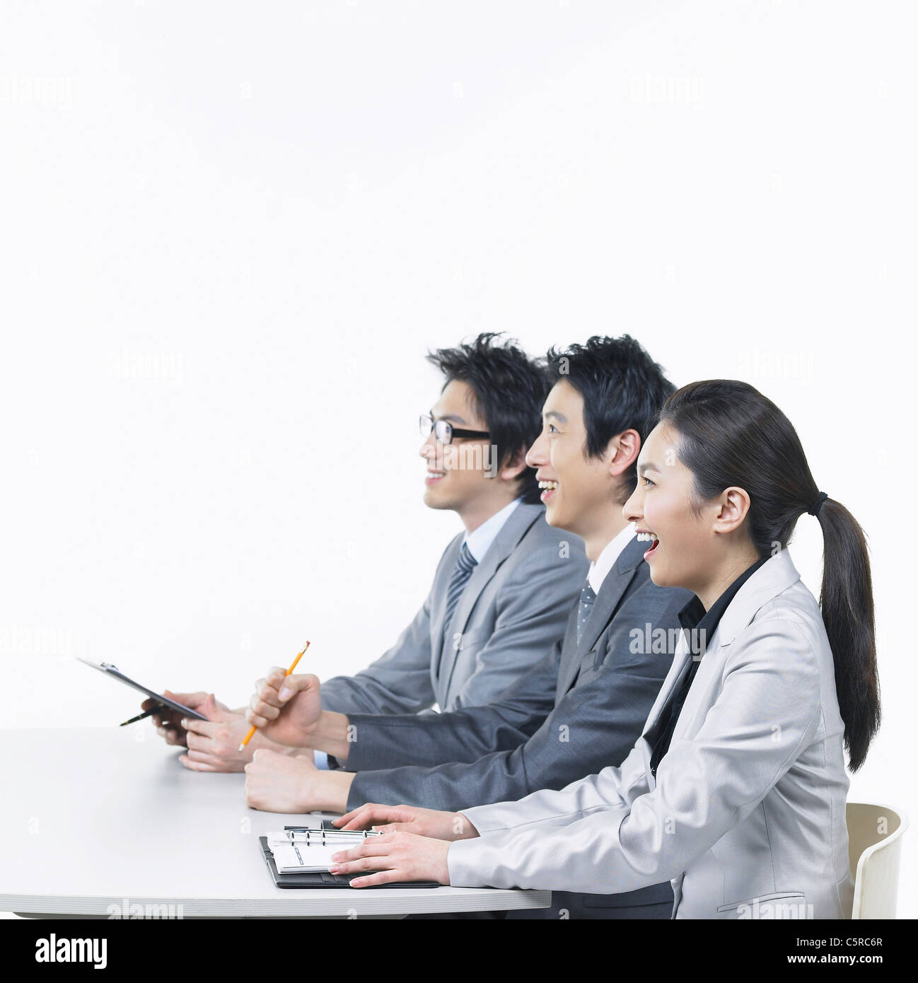 Three people sitting on a desk Stock Photo - Alamy