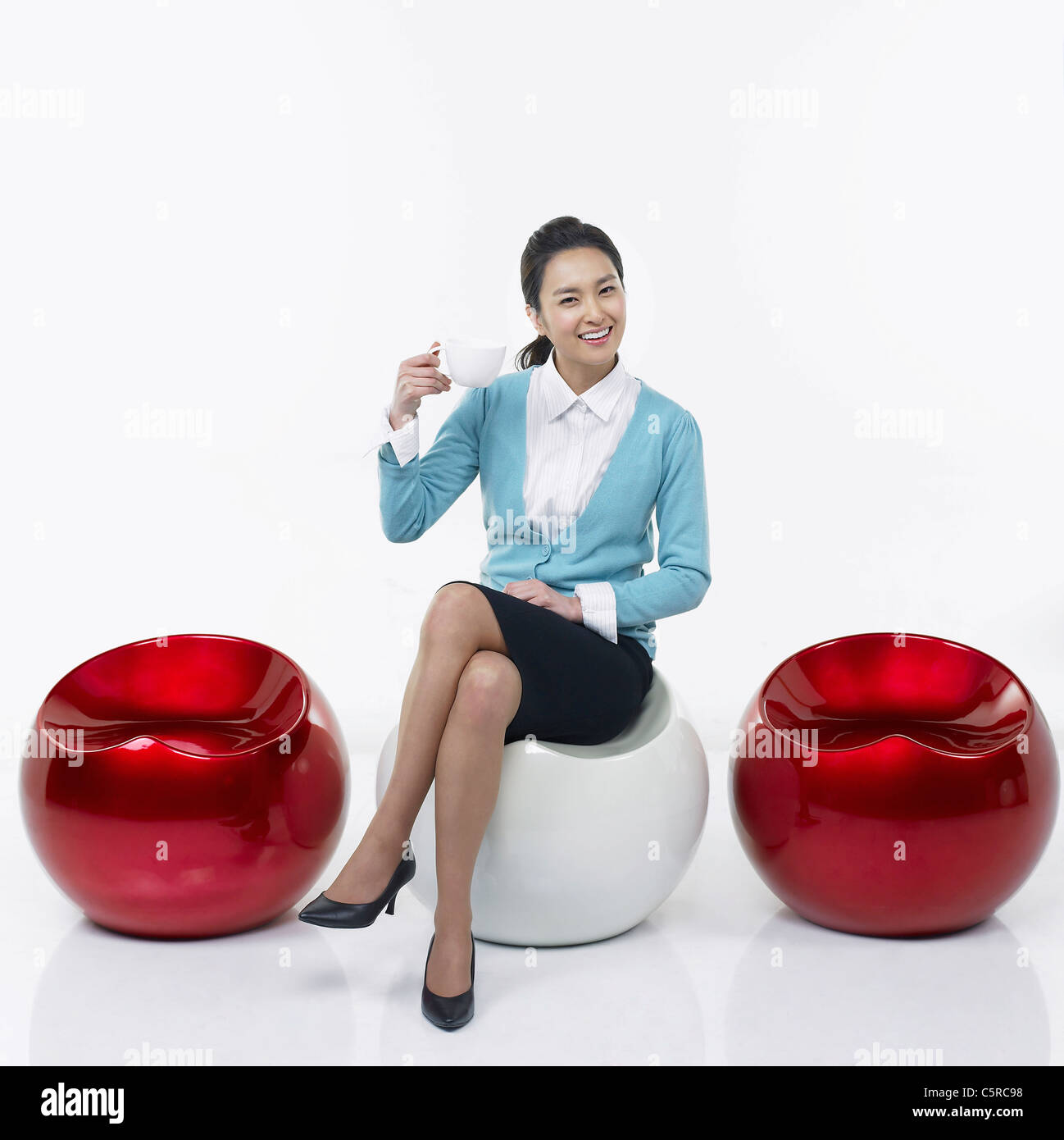 A woman having tea sitting on a chair Stock Photo - Alamy