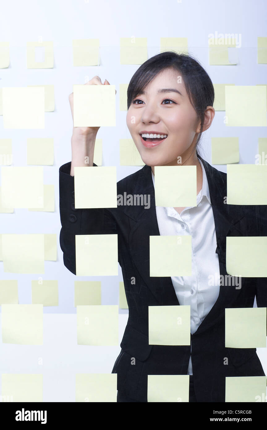 A business woman writing on one of the post its Stock Photo - Alamy