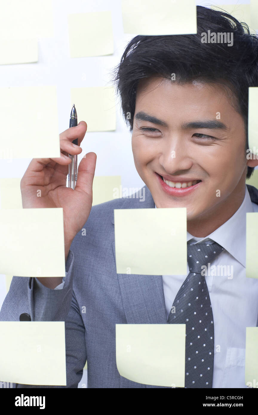 A business man smiling in front of post its Stock Photo - Alamy