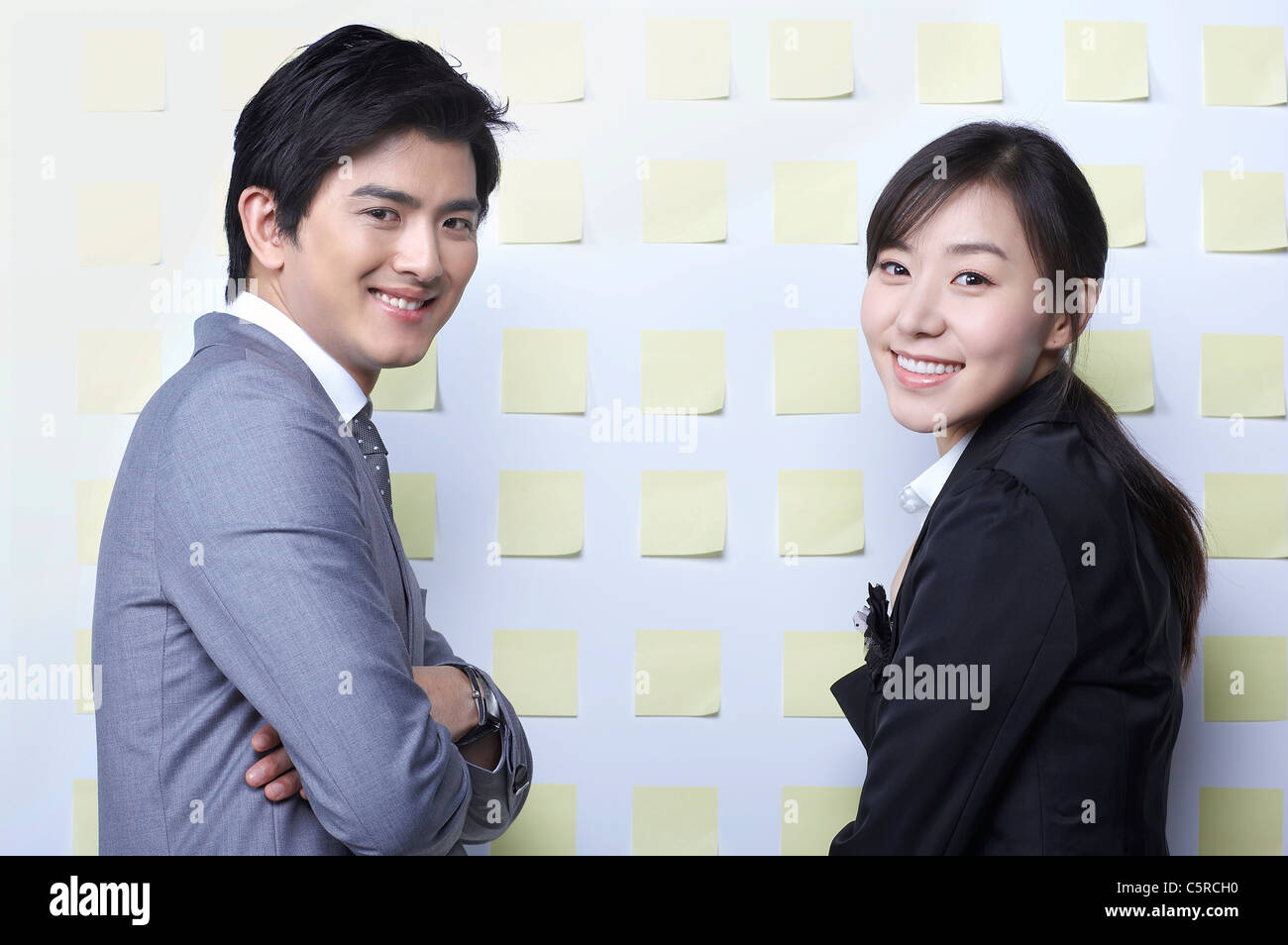 Two people smiling before the papers on the wall Stock Photo - Alamy