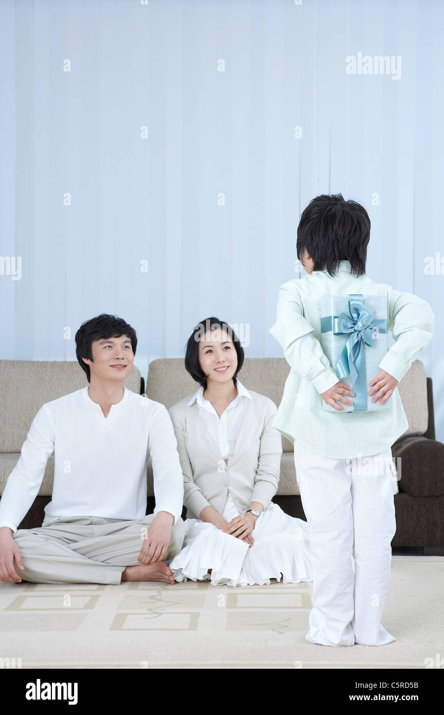 A boy hiding a present in front of his parents Stock Photo - Alamy