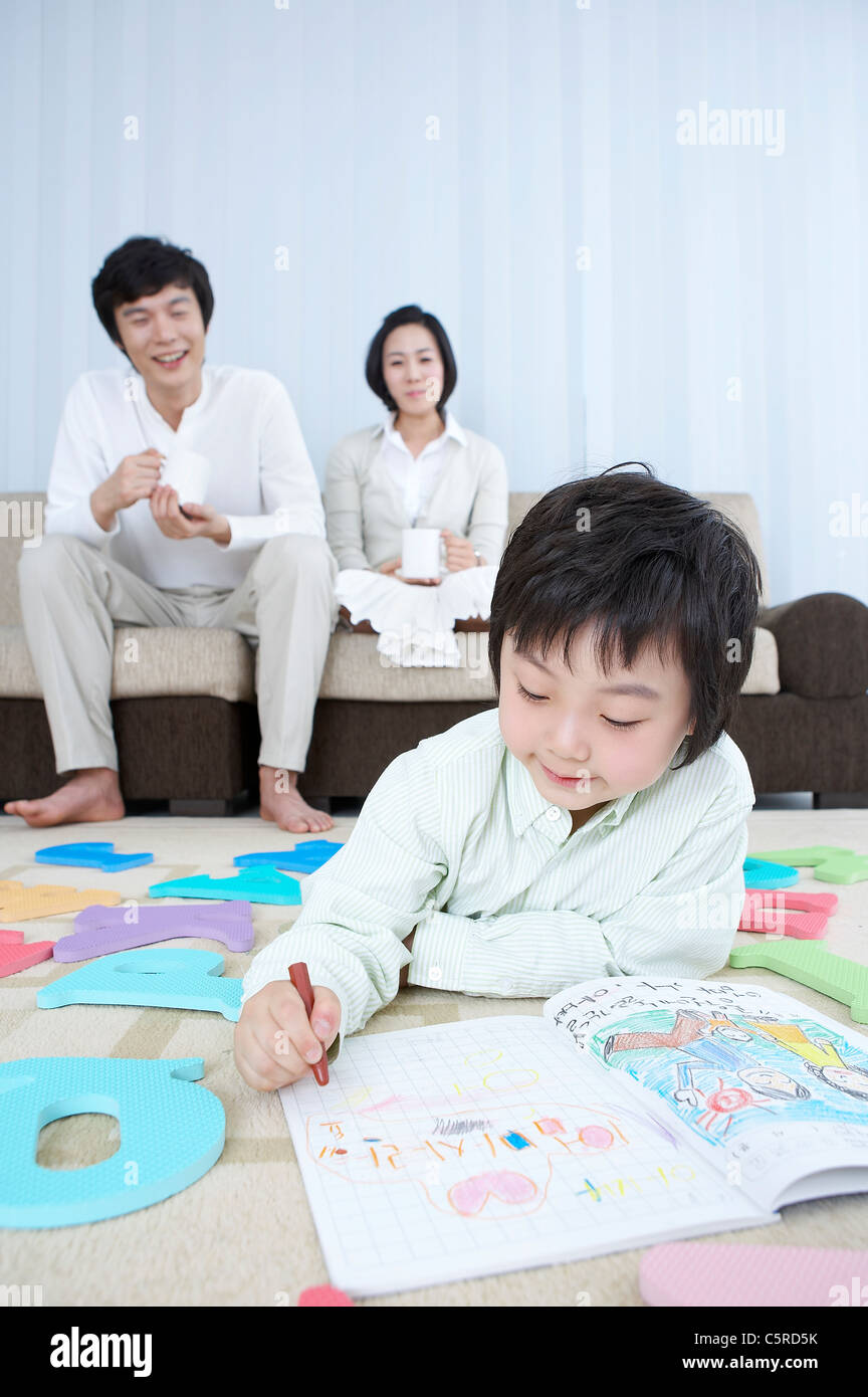 A boy writing in the notebook and his parents looking at him Stock ...