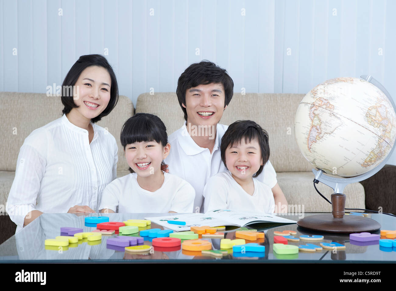 Four family members smiling together in front of a table Stock Photo ...
