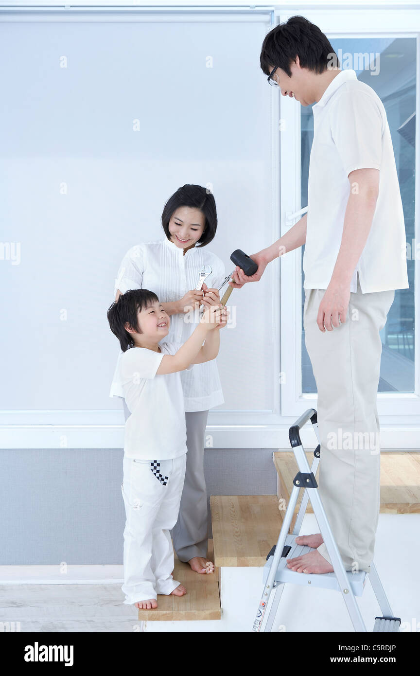A boy giving a hammer to his father Stock Photo - Alamy