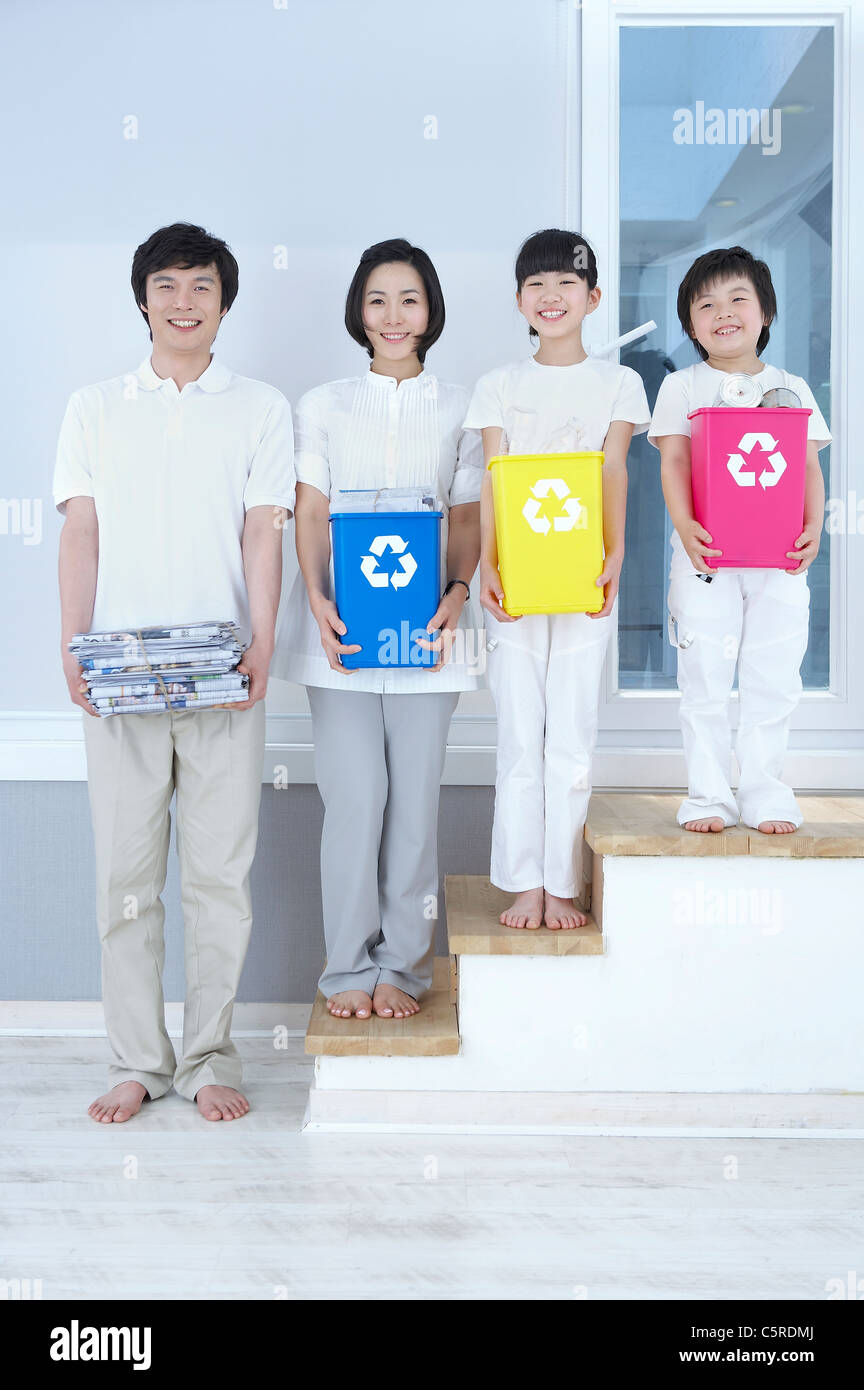 A family holding recycle bin and newspapers Stock Photo - Alamy