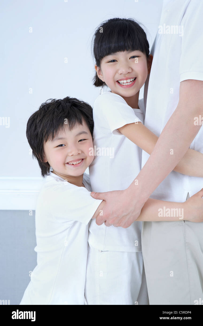 Two children hugging together with their parent Stock Photo - Alamy