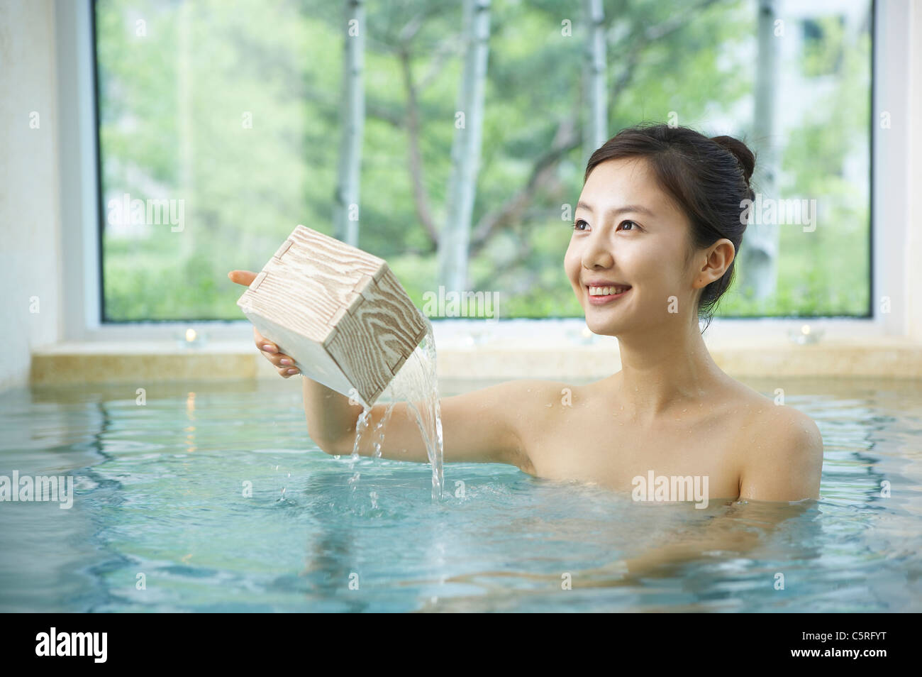 A woman inside water holding a wooden bucket Stock Photo - Alamy