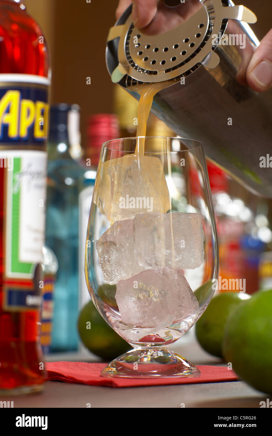 Human hand pouring drink out of cocktail shaker into glass, close up ...