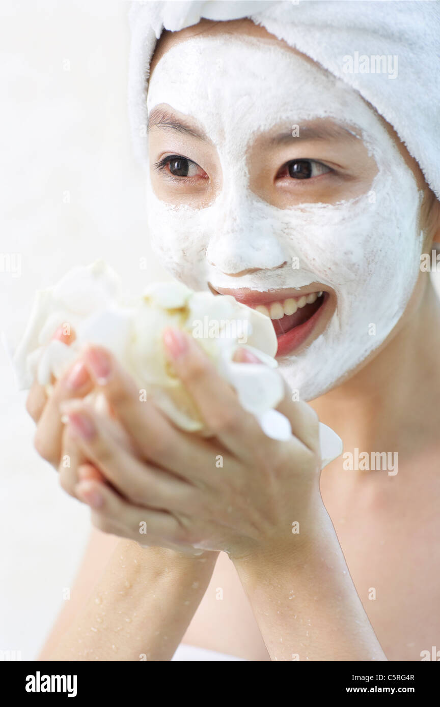 A woman applying facial pack holding flowers Stock Photo - Alamy