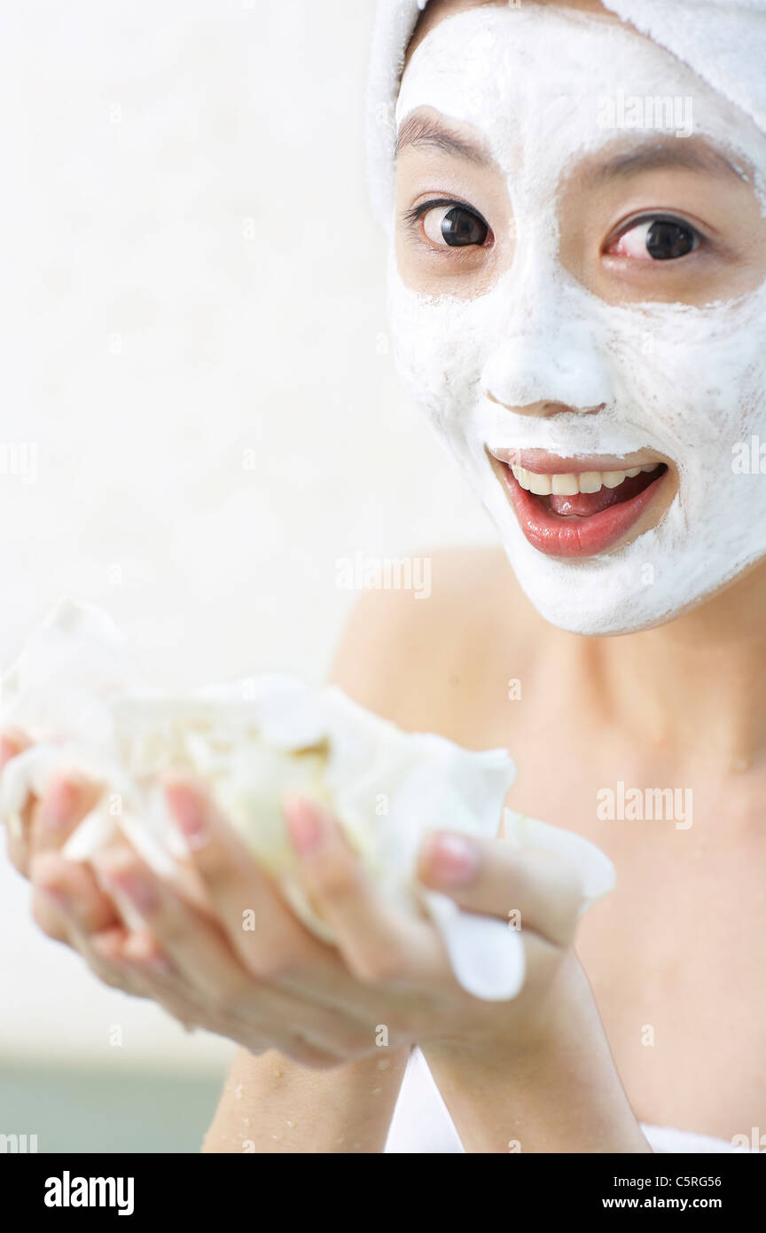 A woman applying facial pack holding flowers Stock Photo - Alamy