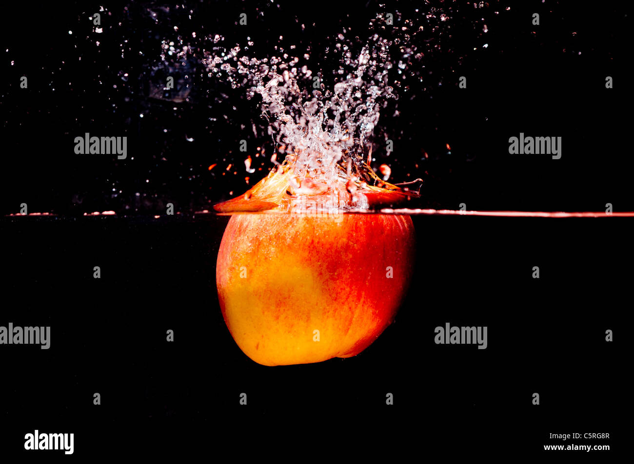 Apple dropped into water on a black background Stock Photo - Alamy