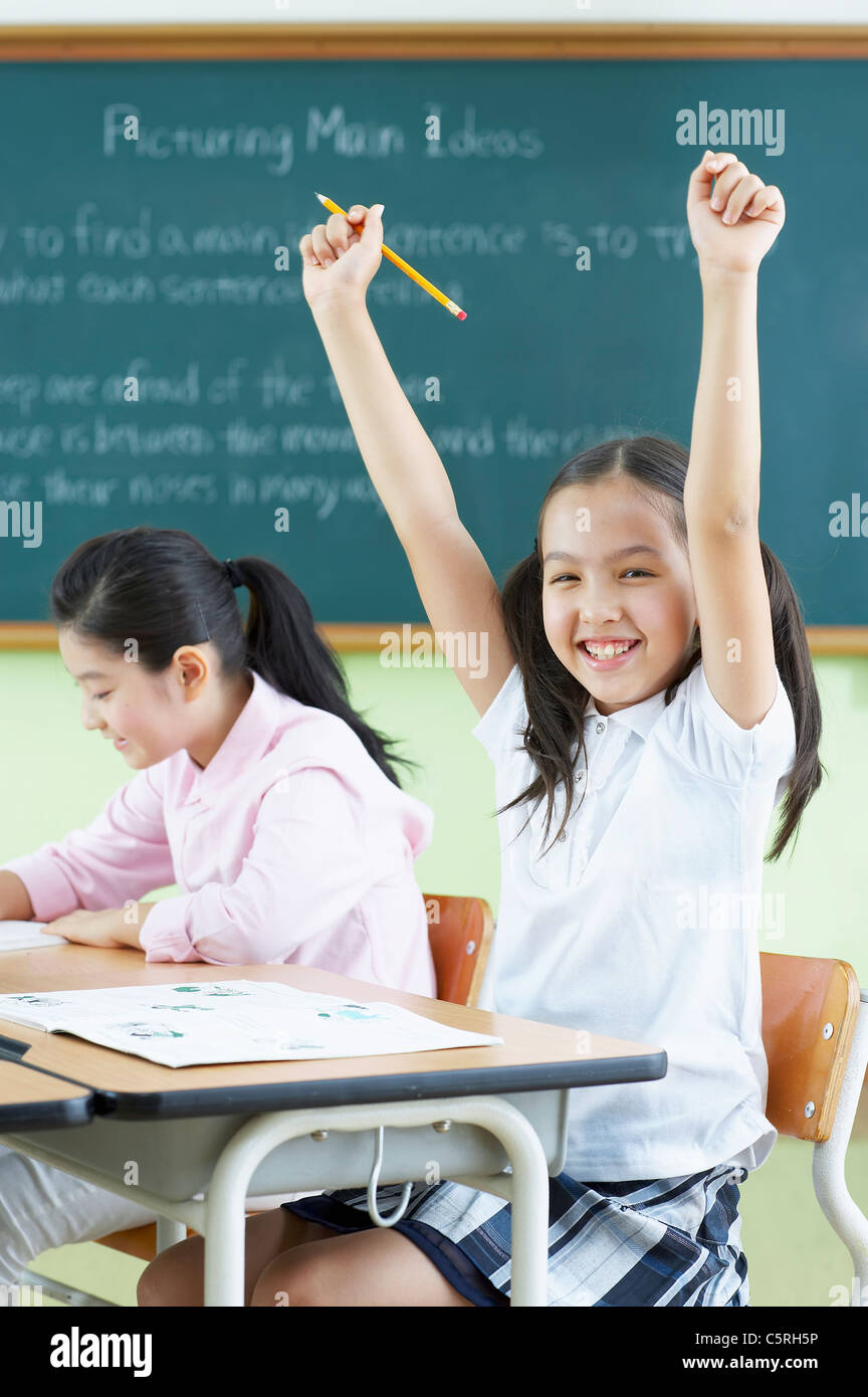Two Asian girls sitting at desks Stock Photo - Alamy