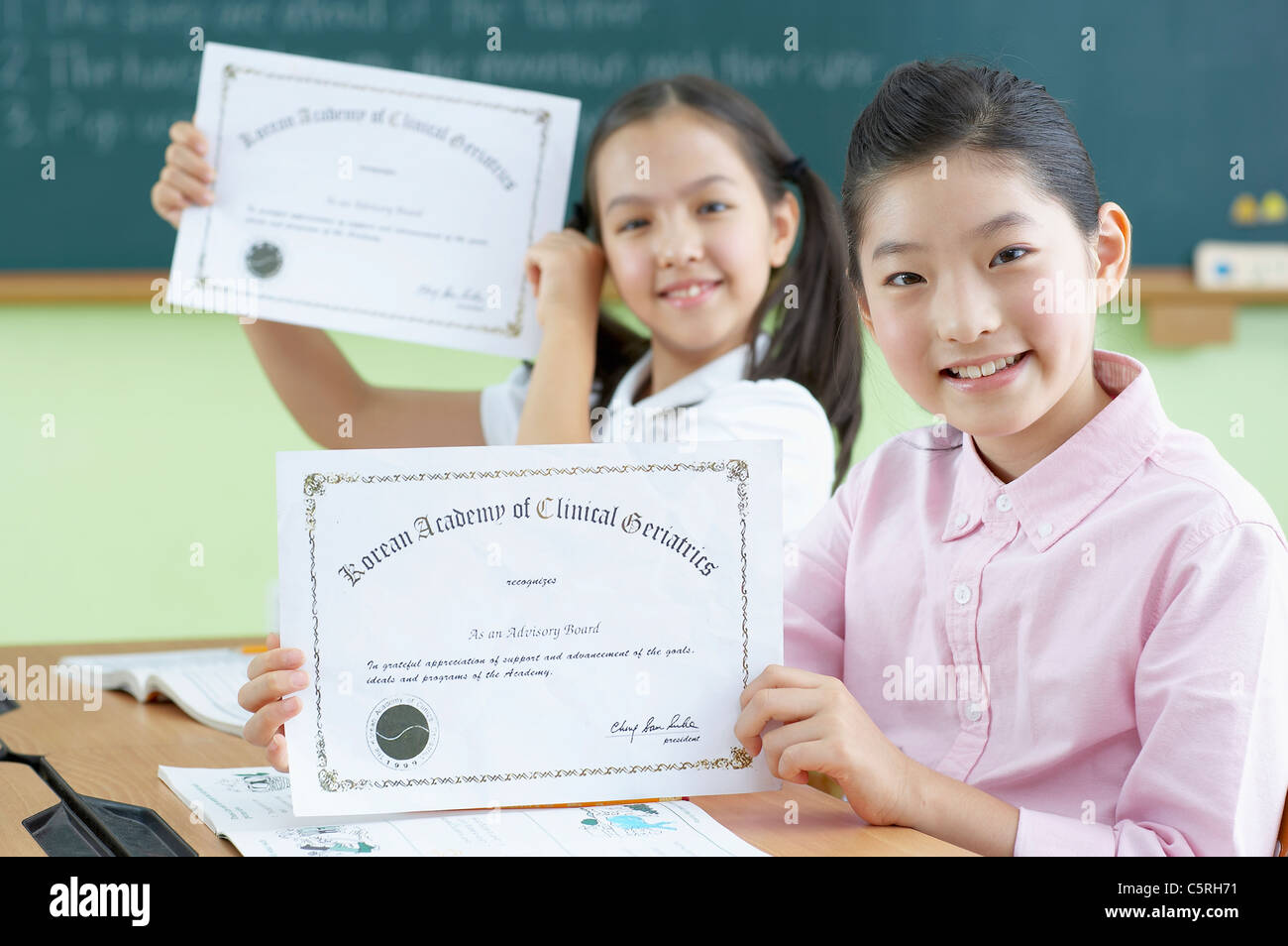 Two Asian girls holding certificates Stock Photo - Alamy
