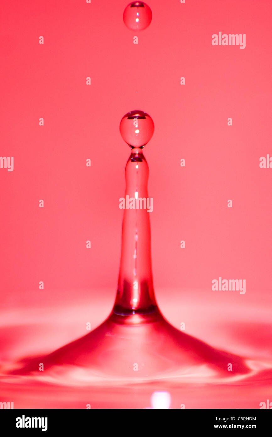 A splash of water, captured against a red background Stock Photo - Alamy