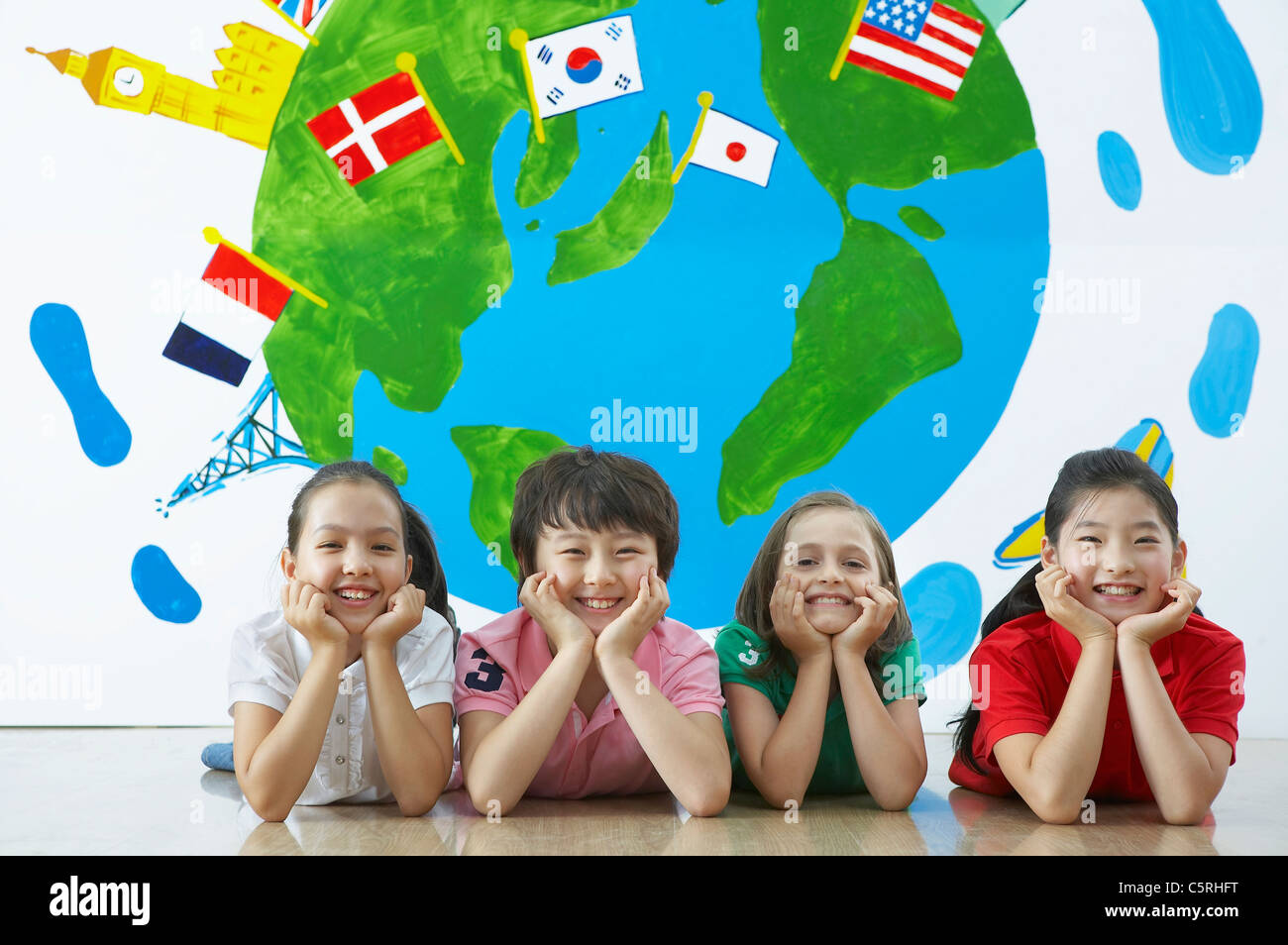 Four students lying on their stomach on the floor Stock Photo - Alamy