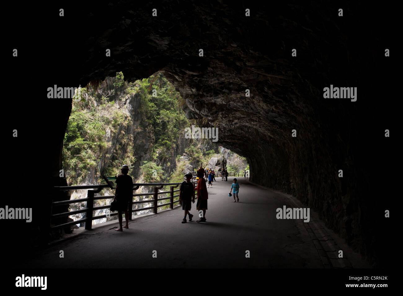 Visitors walk through cliffside tunnel's galleries, under rock overhang ...