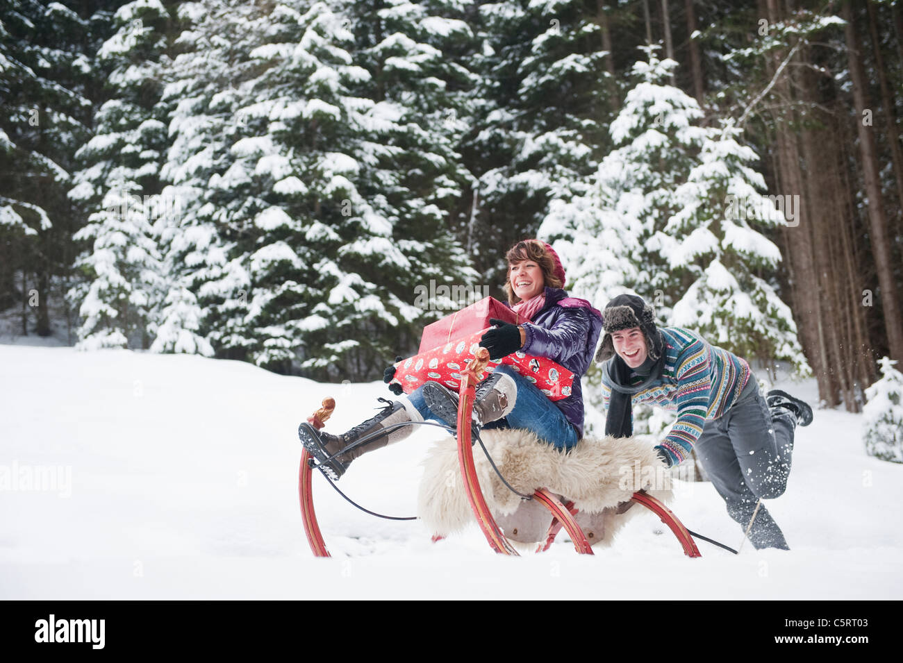 Austria, Salzburg Country, Flachau, Young woman sitting on sledge with ...