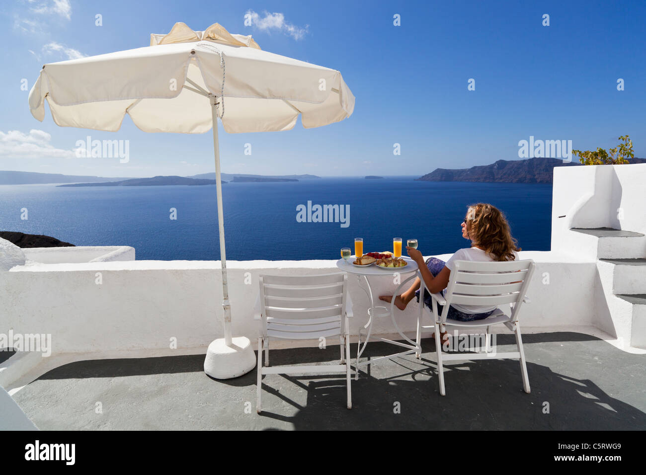 Greece, Cyclades,Thira, Santorini, Oia, Mature woman relaxing with blue ...