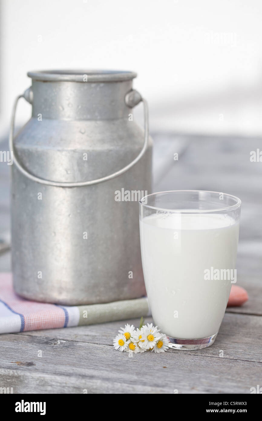 Germany, Close up of milk churn and milk glass on wooden table Stock ...