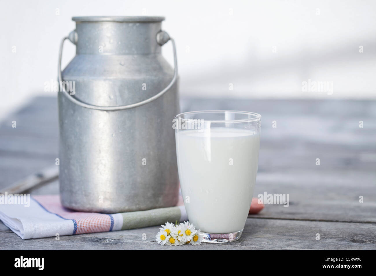 Germany, Close up of milk churn and milk glass on wooden table Stock ...