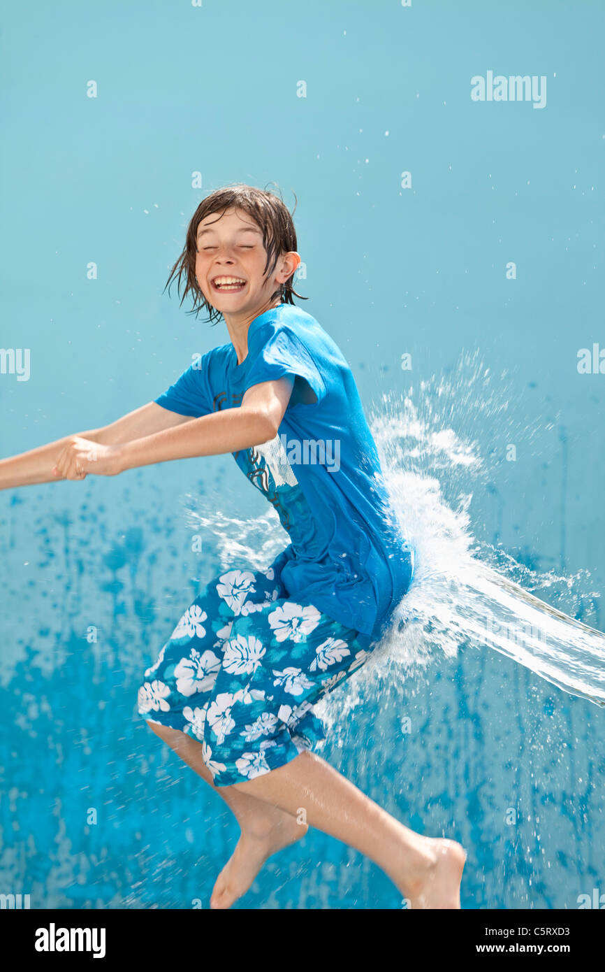 Germany, Boy jumping in splash of water against blue background Stock ...