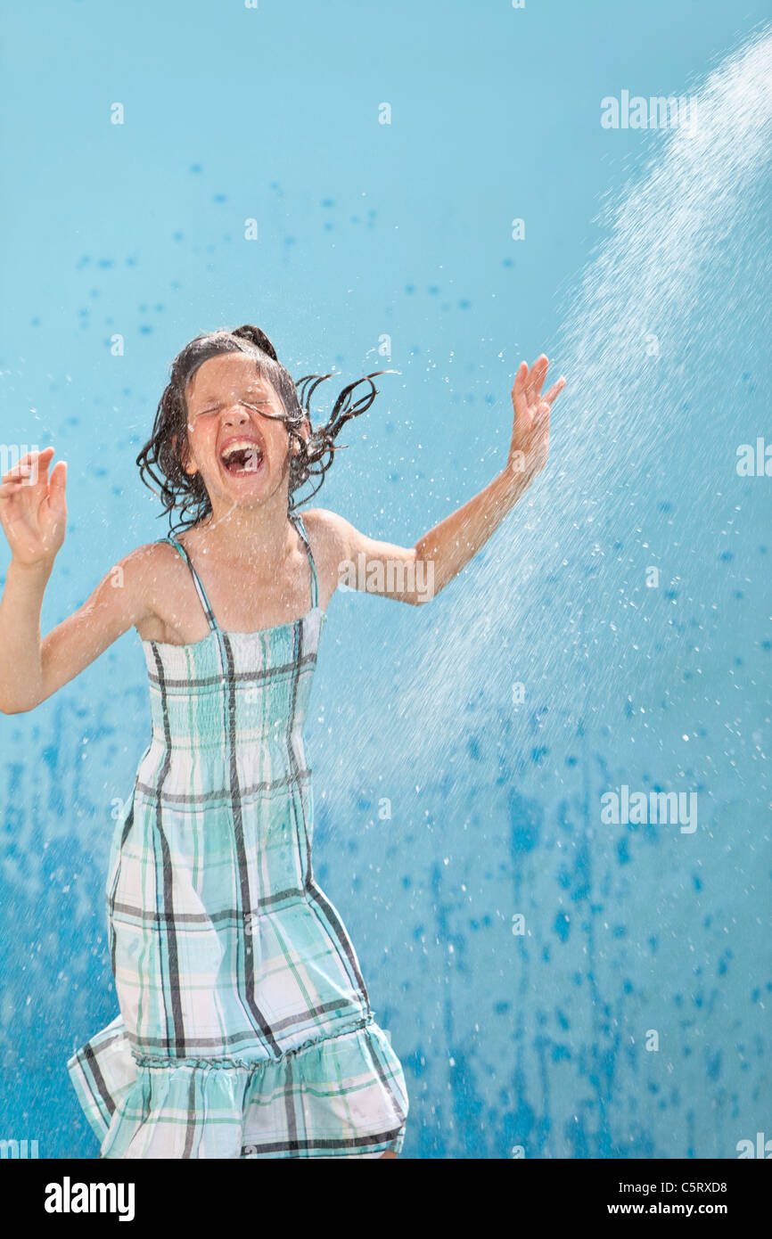 Germany, Girl jumping in splash of water against blue background Stock ...