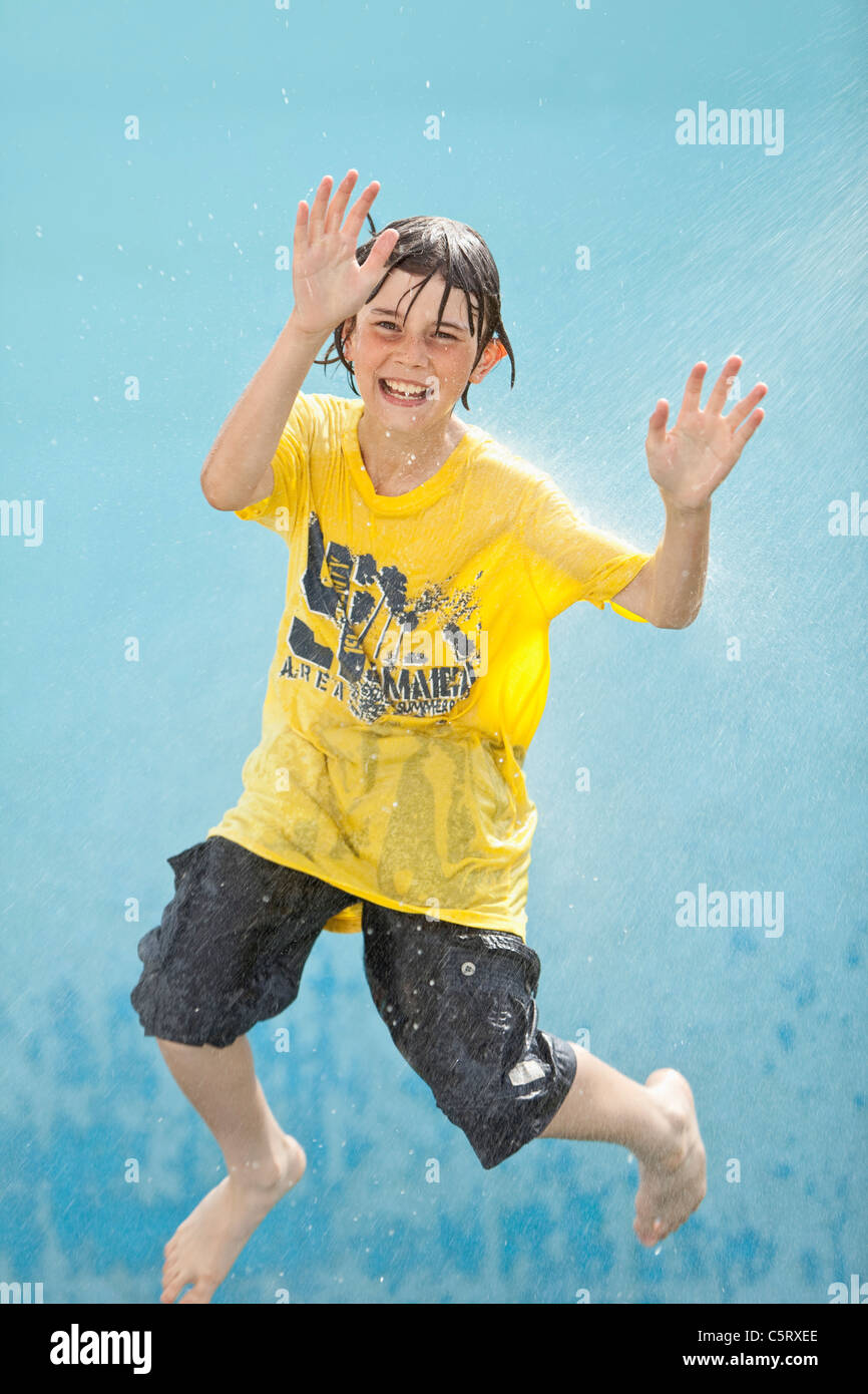 Germany, Boy jumping in splash of water against blue background Stock ...