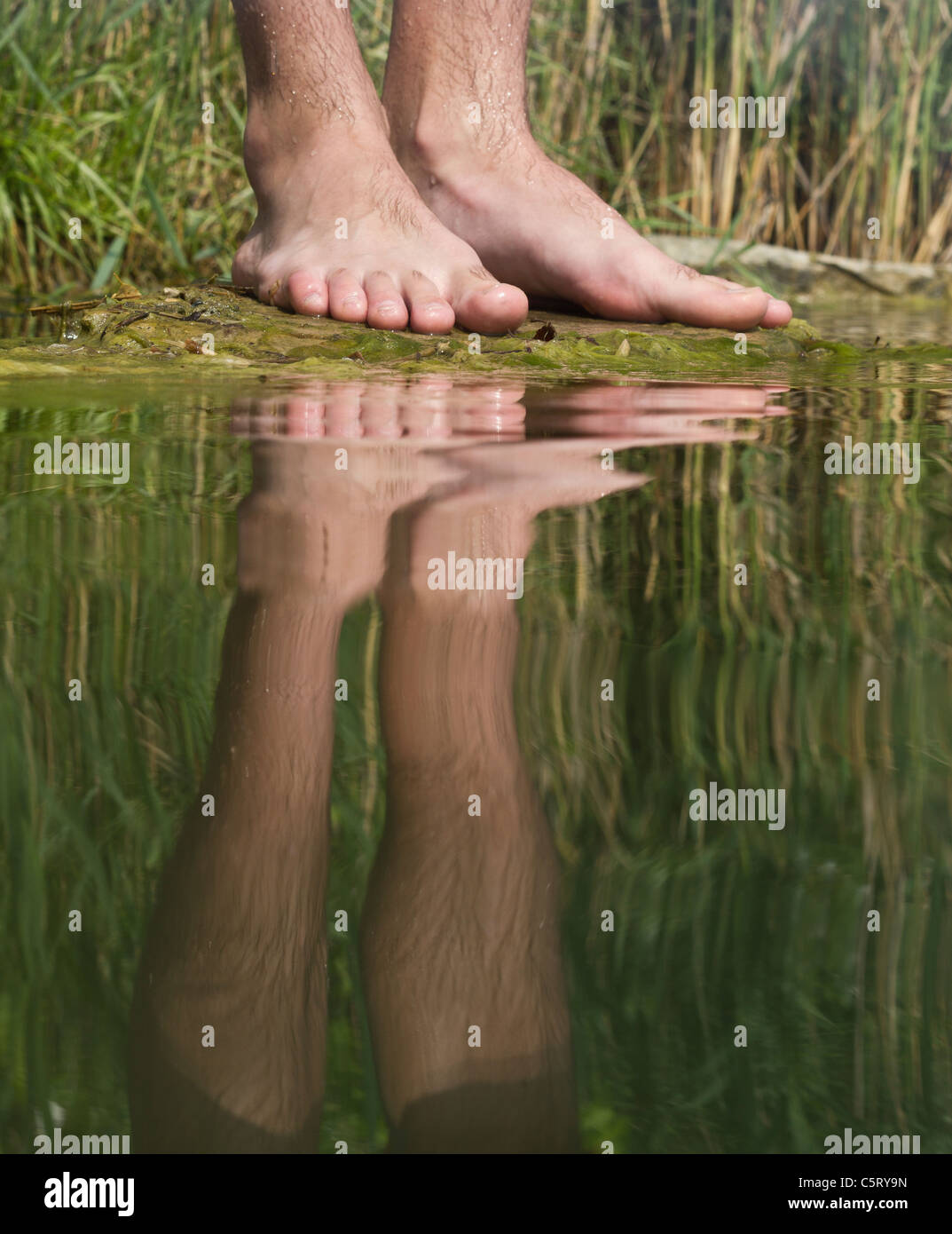 Austria, Vienna, Reflection of man's feet on lakeshore, close up Stock ...