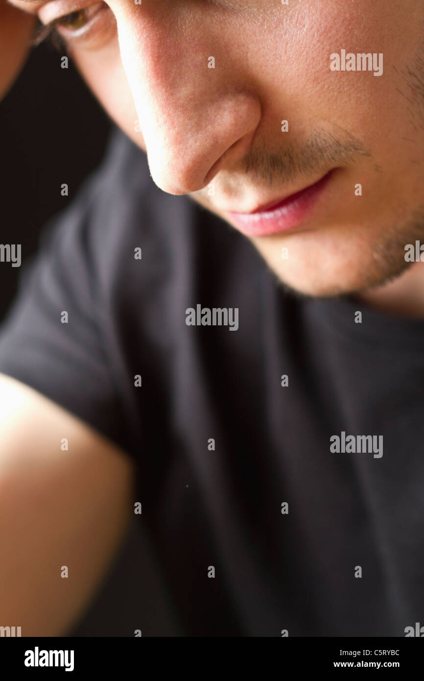 Close up of young man against black background, looking down Stock ...