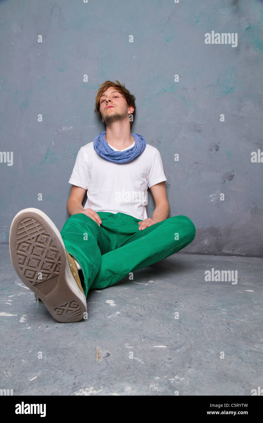 Young man sitting and leaning agaist dirty wall, portrait Stock Photo ...