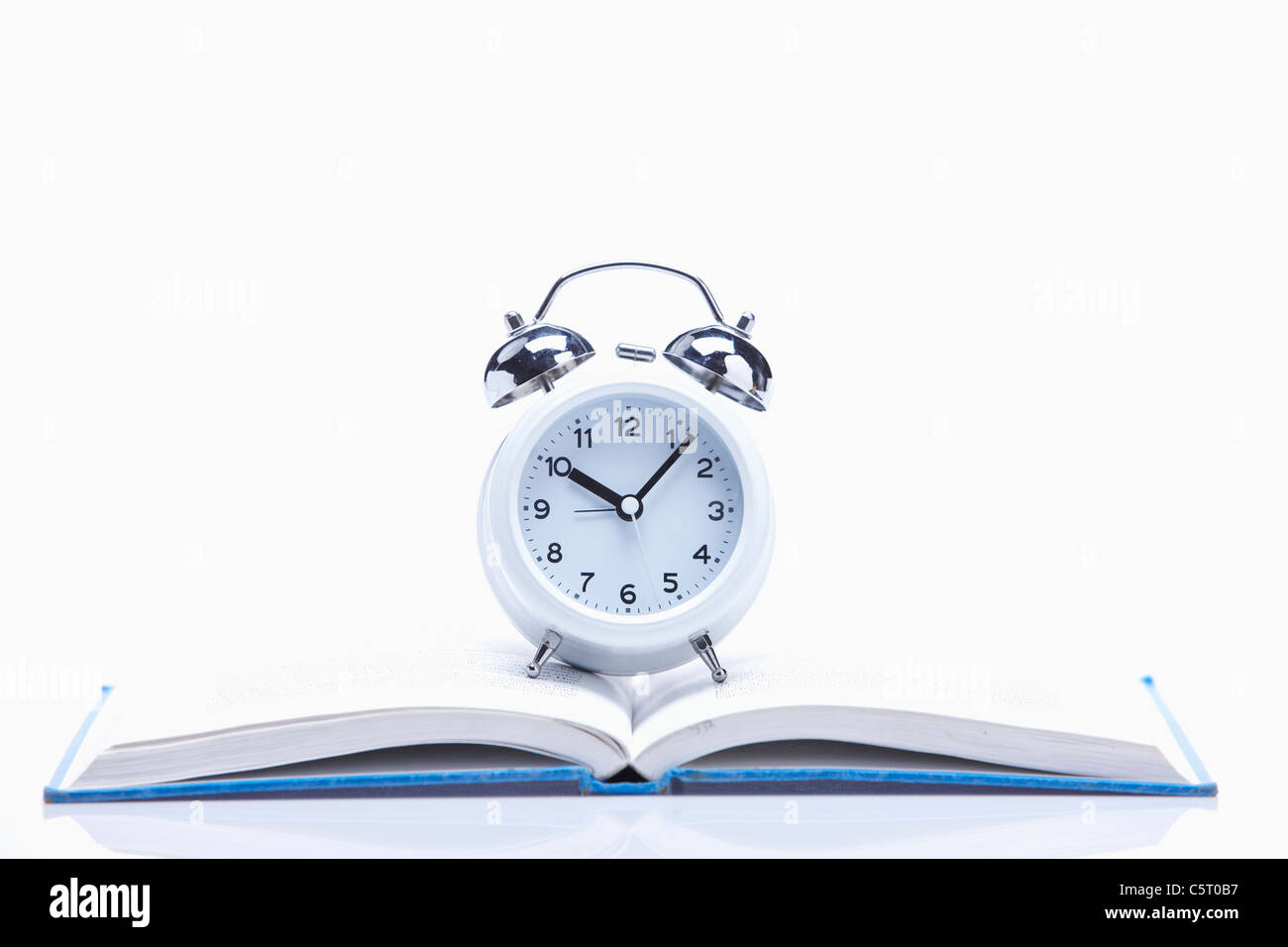 clock on the book Stock Photo - Alamy