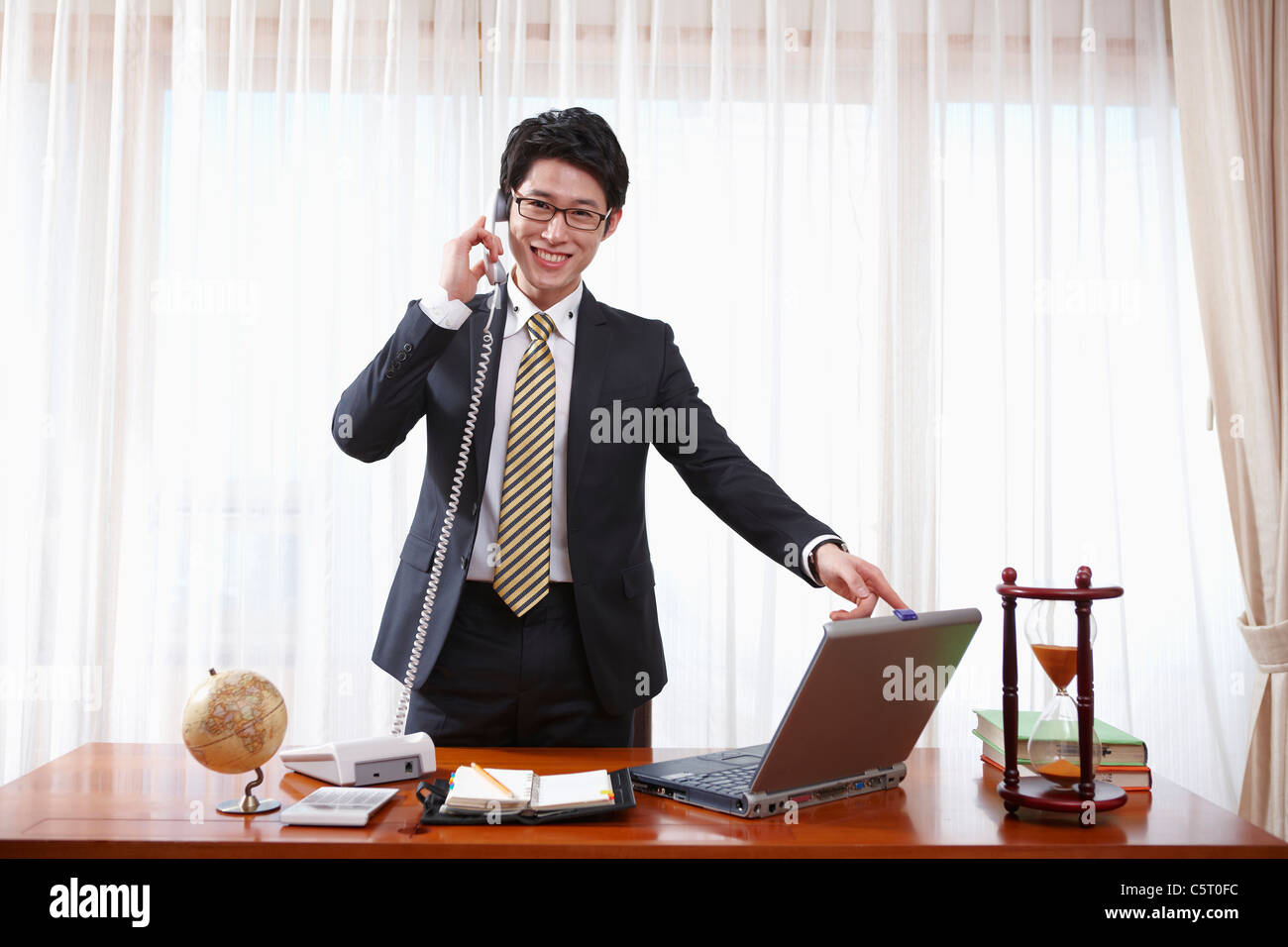 man answering the phone on the desk Stock Photo - Alamy