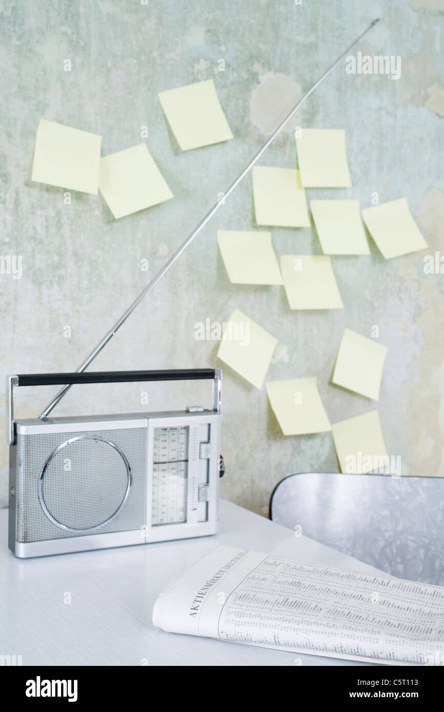 Radio and newspaper on table, blank adhesive notes on wall Stock Photo ...