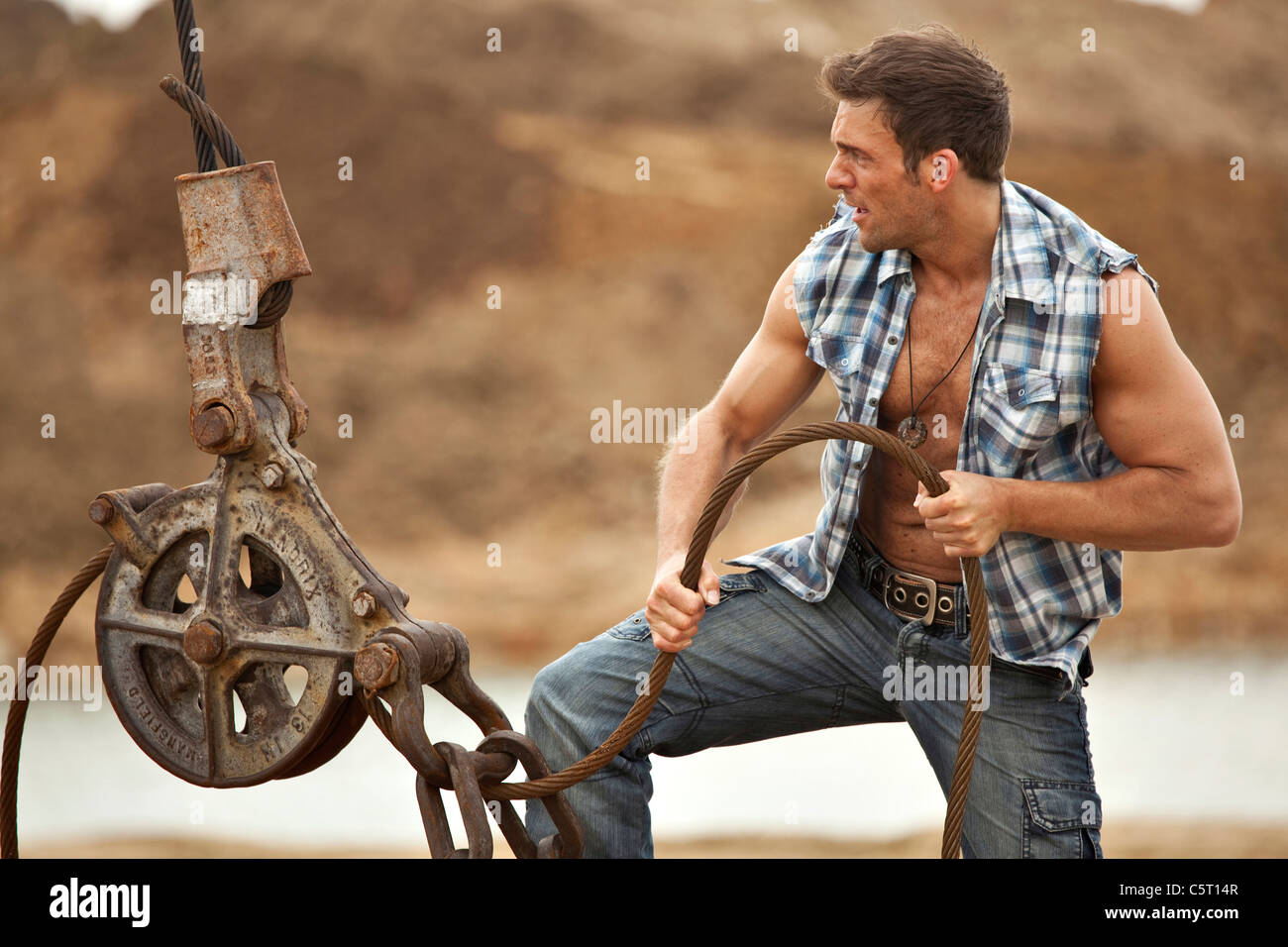 Germany, Bavaria, Man pulling chain with quarry pond in background ...