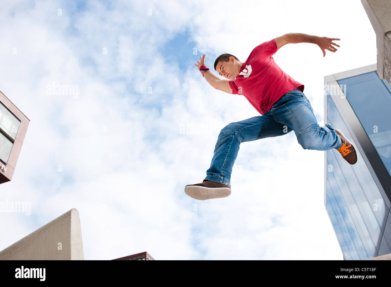 Jumping young man in front of buildings Stock Photo - Alamy