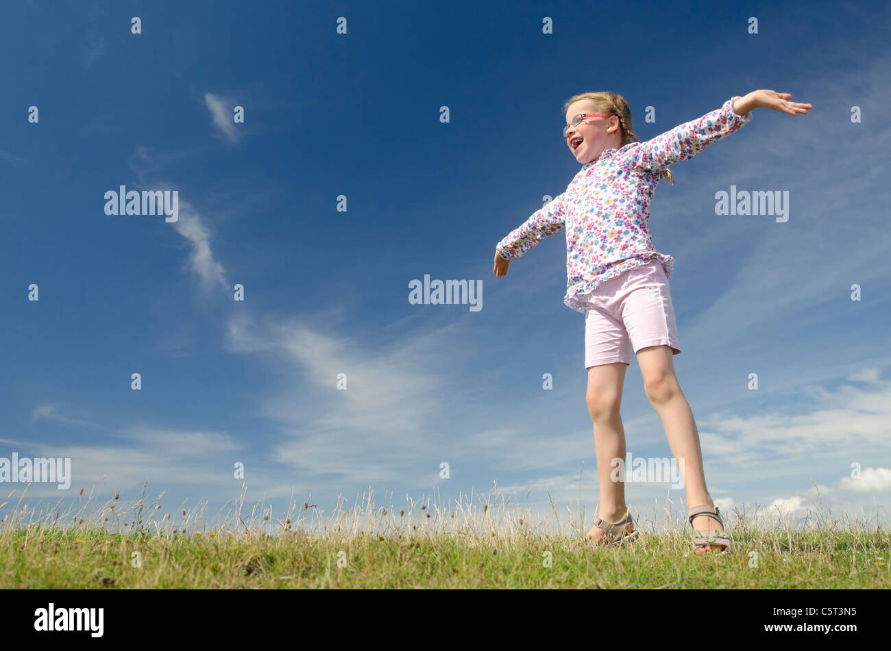 Happy little girl jumping in front of blue sky Stock Photo - Alamy