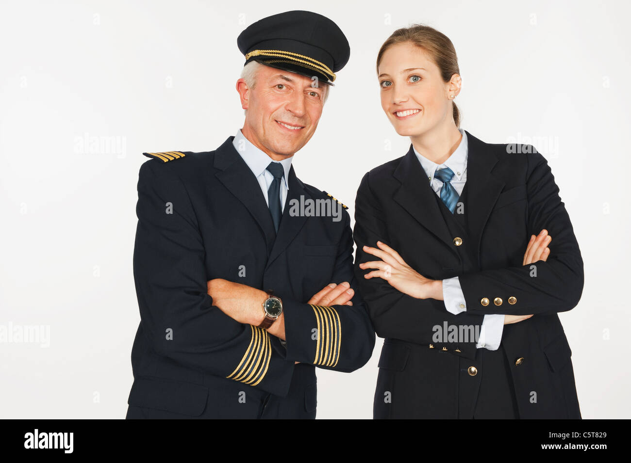 Senior captain and young air stewardess against white background ...