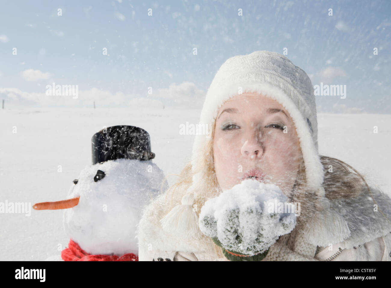Germany, Bavaria, Munich, Young woman blowing snow off hand, portrait Stock Photo - Alamy