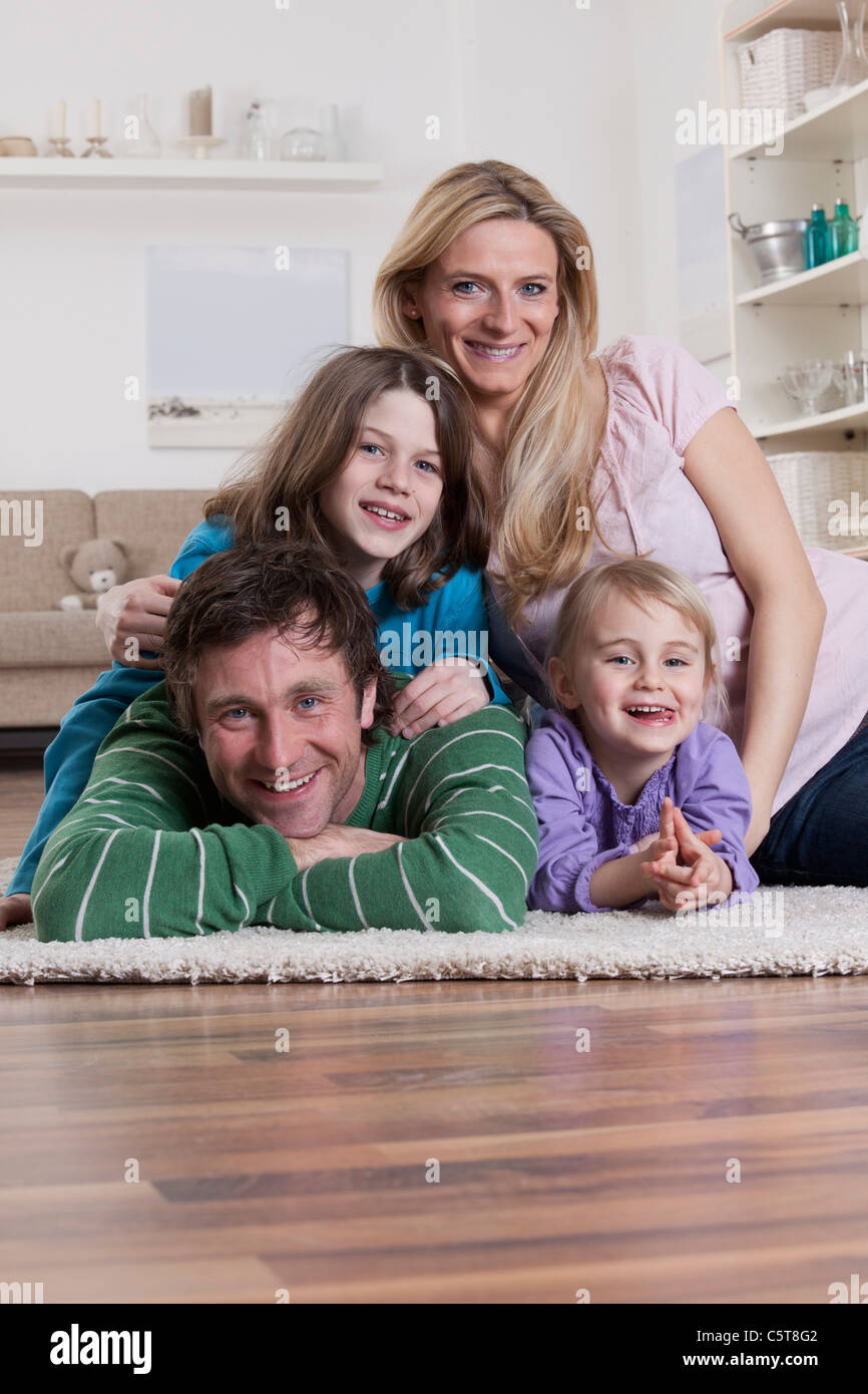 Germany, Bavaria, Munich, Family lying on carpet, smiling, portrait ...