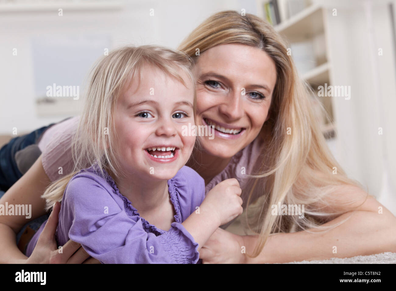 Germany, Bavaria, Munich, Mother and daughter lying, smiling, portrait ...