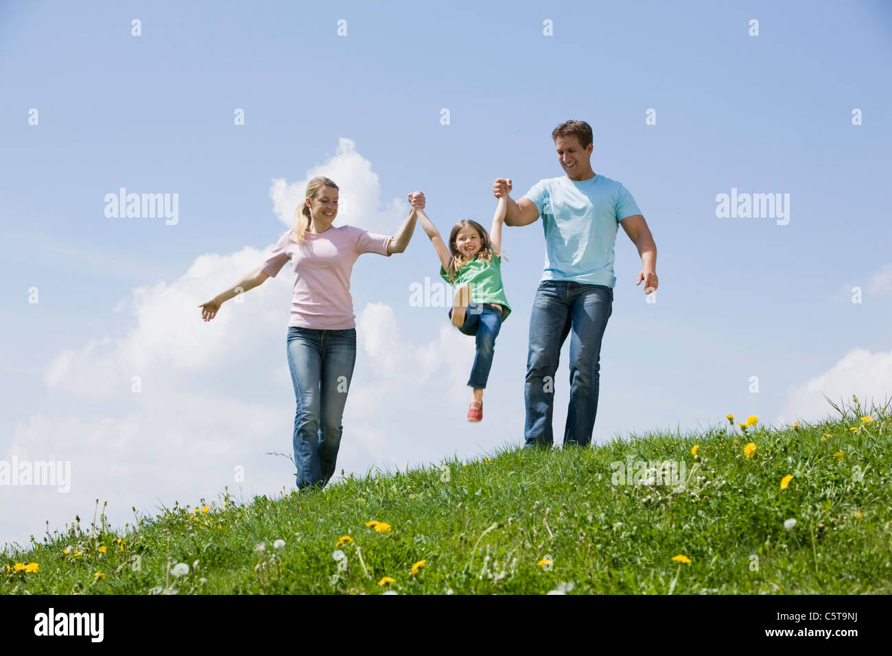Germany, Bavaria, Munich, Parents with child (6-7) walking in meadow ...