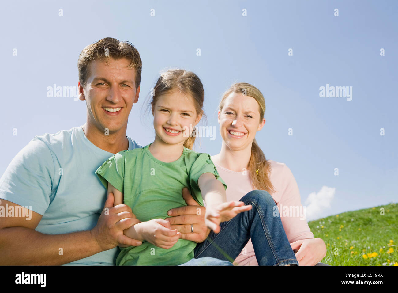 Germany, Bavaria, Munich, Family sitting in meadow, smiling, portrait ...