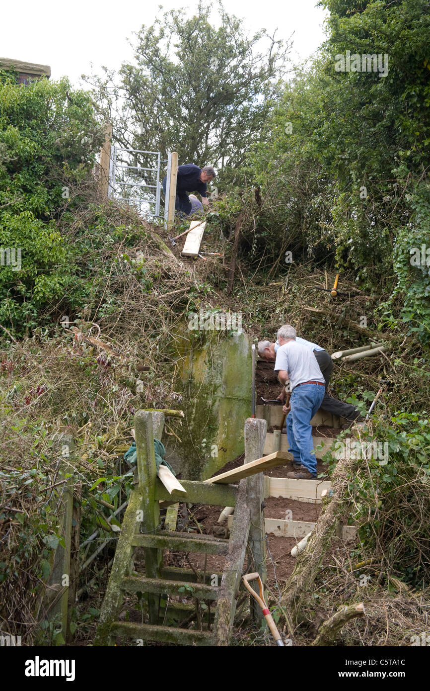 UK Male volunteers constructing steps up to a newly installed gate on a ...